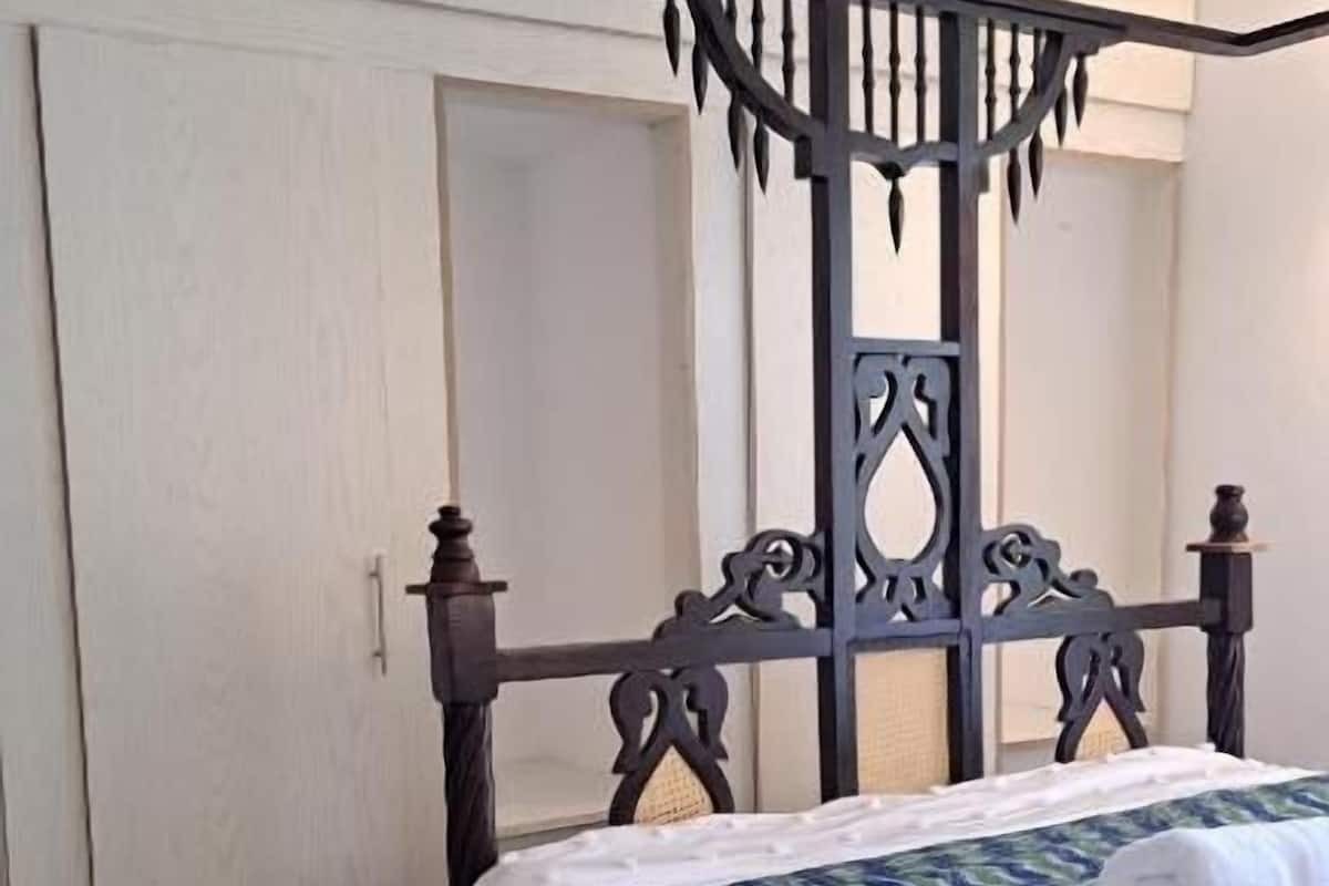 Quarto com cama de dossel, guarda-roupa e chão de azulejos.