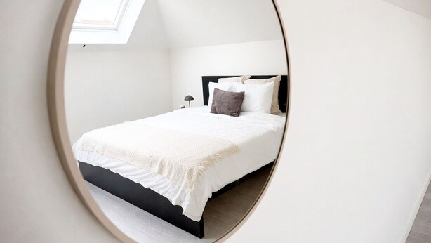 Quarto com cama, mesa de cabeceira, abajur e janela.