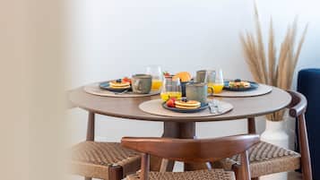 Uma mesa de jantar redonda com um jogo americano, uma pilha de panquecas, um copo de suco de laranja e uma caneca.