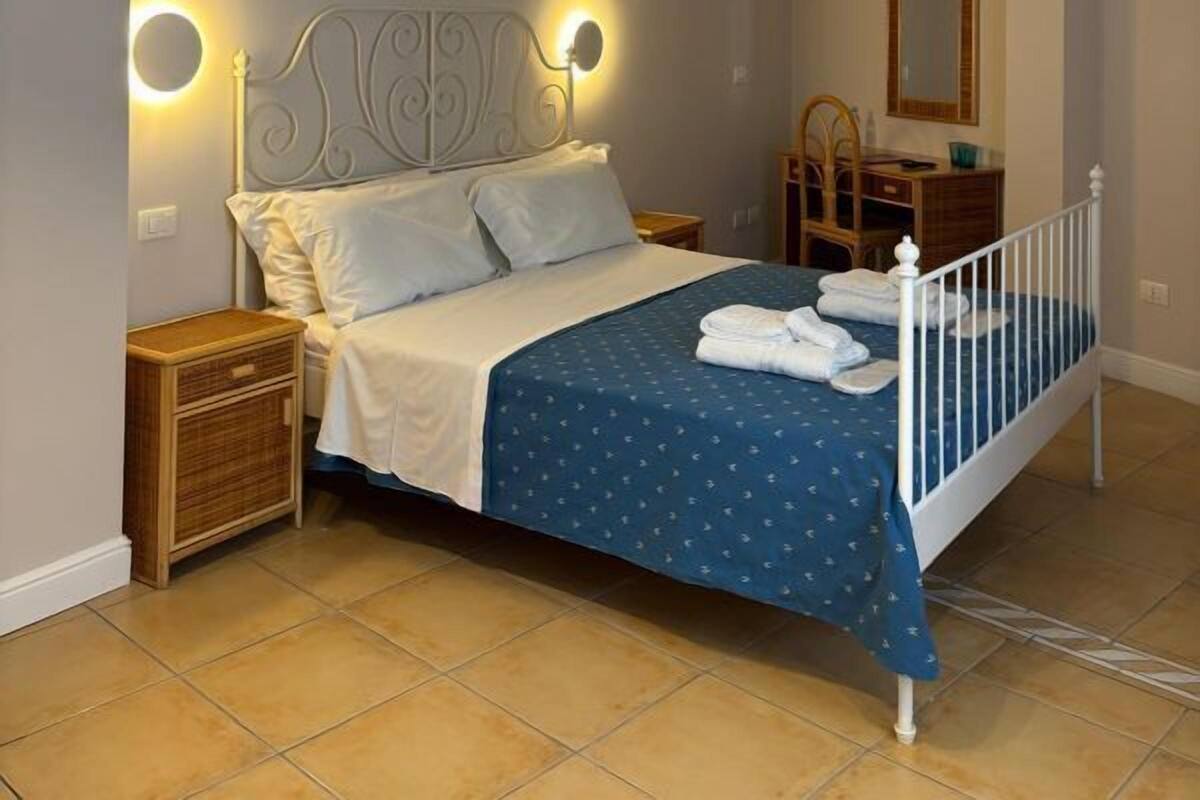 Um quarto com uma cama, mesas de cabeceira, um espelho e uma luminária no teto.