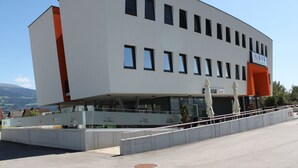 Um edifício moderno com telhado plano, várias janelas e uma placa com a inscrição 'AIS Center'.
