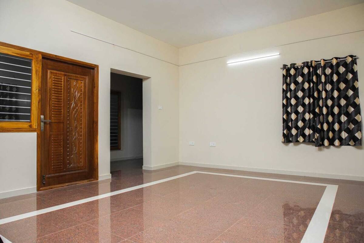 Um quarto com porta de madeira, cortina estampada e chão de azulejos.