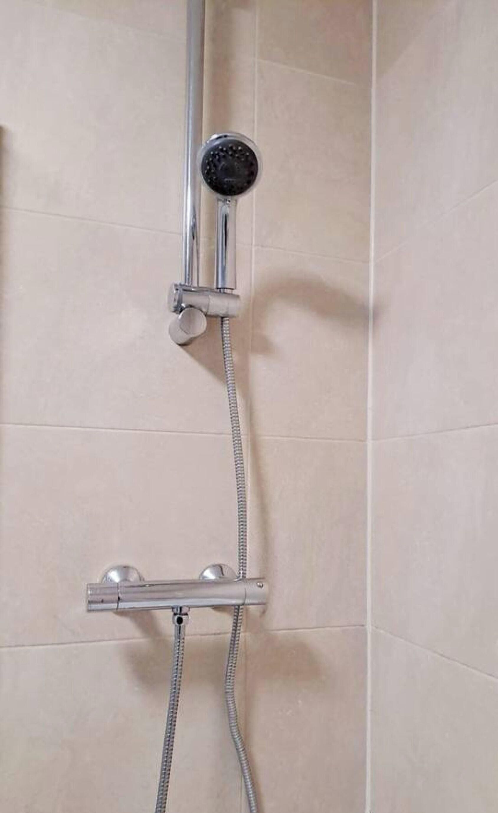 Chuveiro com chuveiro manual e torneira fixa na parede.