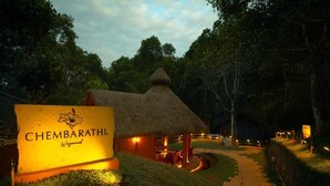 Uma estrutura com telhado de palha e uma placa com a inscrição 'CHEMBARATHI Wayanad'.