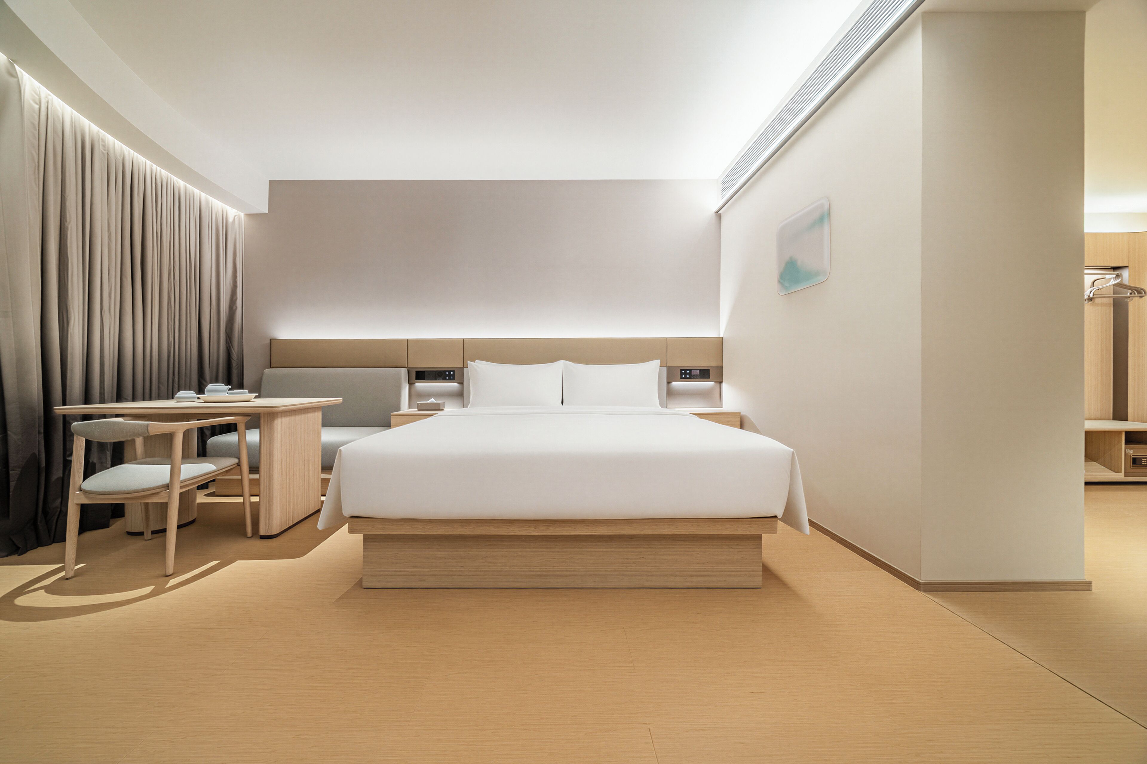 Quarto de hotel moderno com uma cama grande, mesas de cabeceira, uma escrivaninha e uma cadeira.
