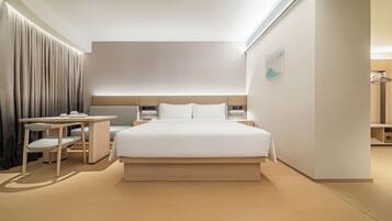 Quarto de hotel moderno com uma cama grande, mesas de cabeceira, uma escrivaninha e uma cadeira.