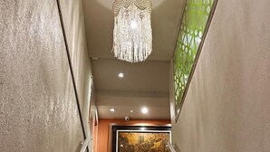 Uma escadaria com degraus de mármore, um candelabro e um quadro na parede.