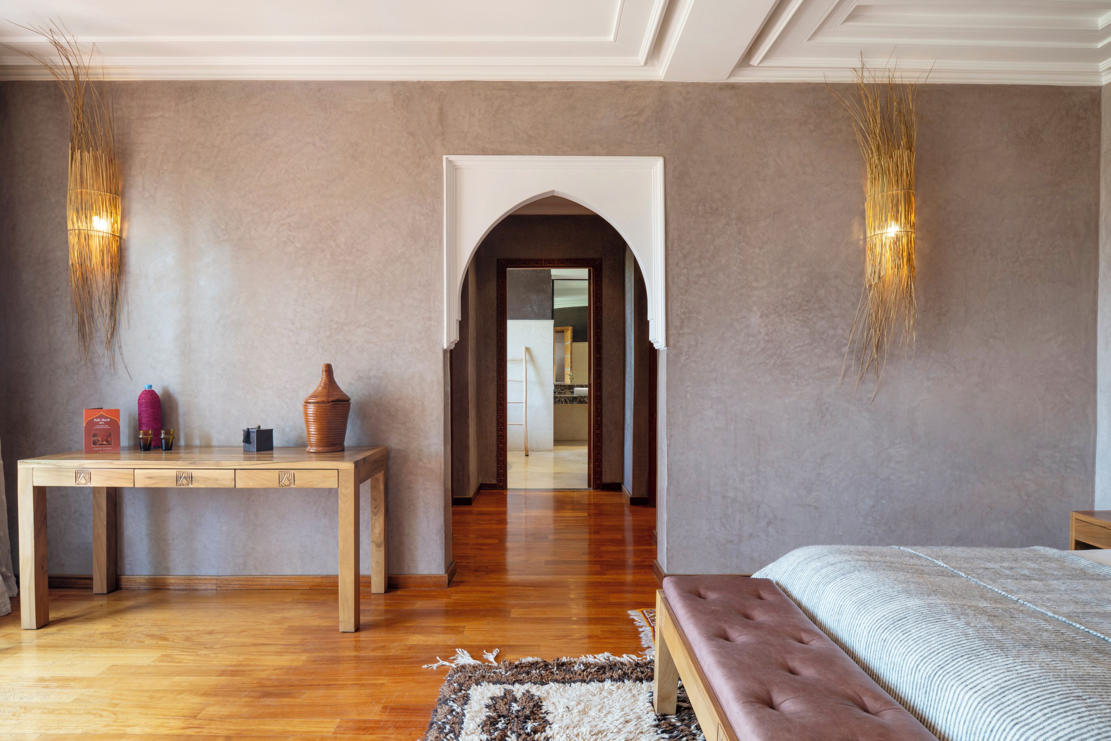 Quarto com cama de madeira, mesa de cabeceira, escrivaninha e espelho.