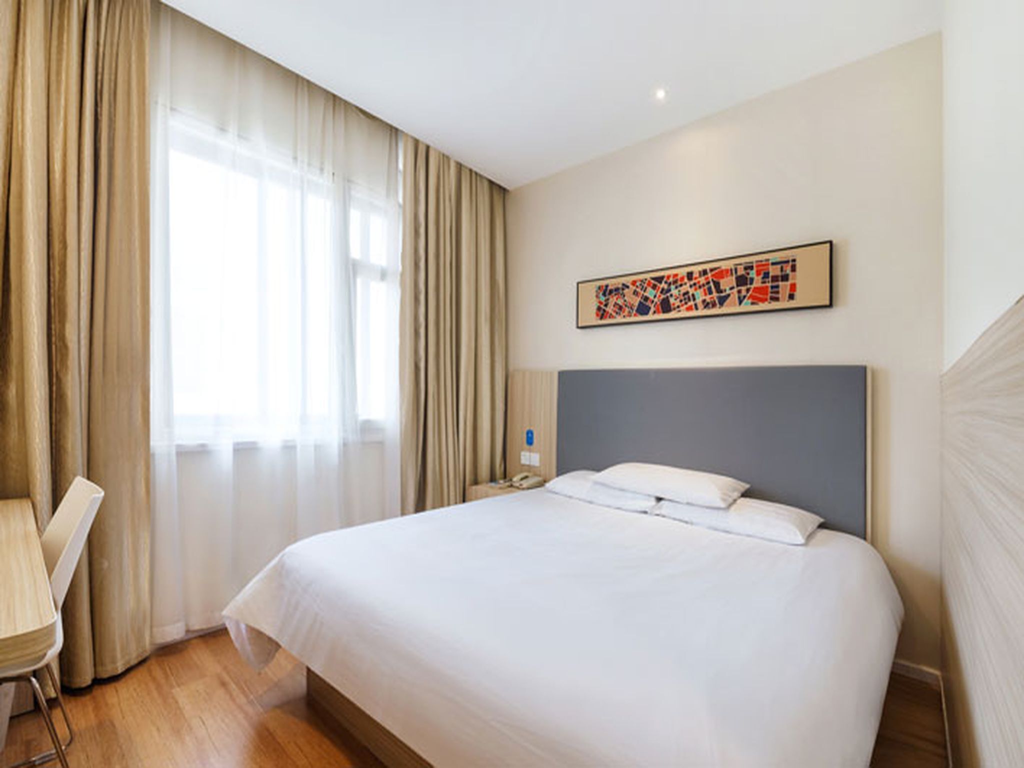 Quarto de hotel com uma cama, uma escrivaninha e uma cadeira.