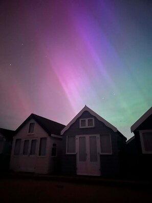 Fileira de casas sob um céu noturno com aurora boreal.