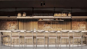 Uma área de bar com banquetas, balcão e garrafas.
