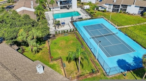 Zona residencial com piscina, quadra de tênis e vegetação ao redor.