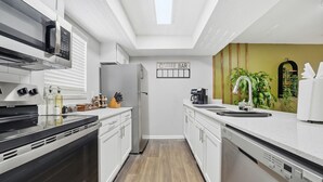 Uma cozinha moderna com um cantinho de café, eletrodomésticos de aço inoxidável e piso de madeira.