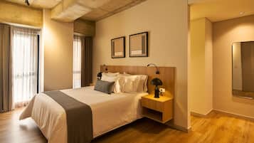 Quarto de hotel com cama grande, mesas de cabeceira, cabeceira de madeira e um espelho na parede.