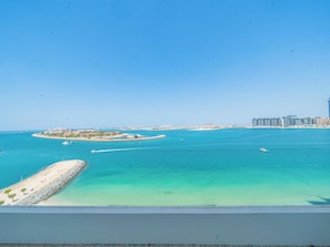 Vista costeira com águas turquesa cristalinas, uma praia arenosa e edifícios ao longe.