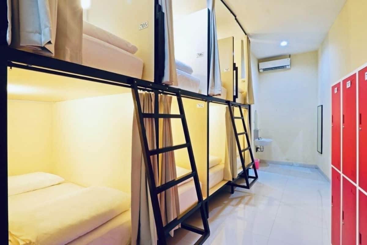 Beliches numerados, uma escada e armários vermelhos em um corredor.