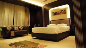 Um quarto com uma cama, um sofá, um ventilador de teto e um quadro na parede.