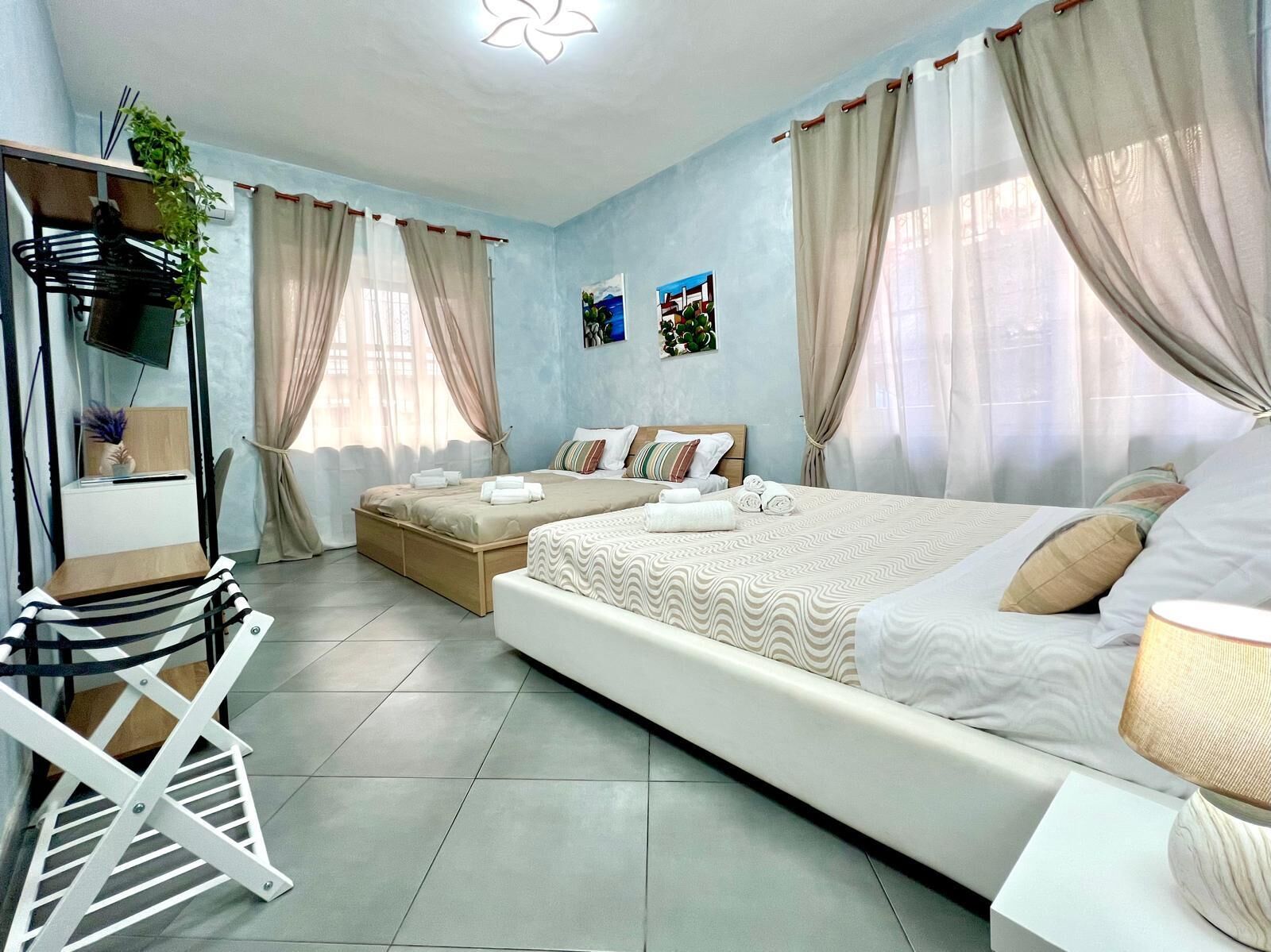 Quarto com cama, escrivaninha, cadeira e televisão.