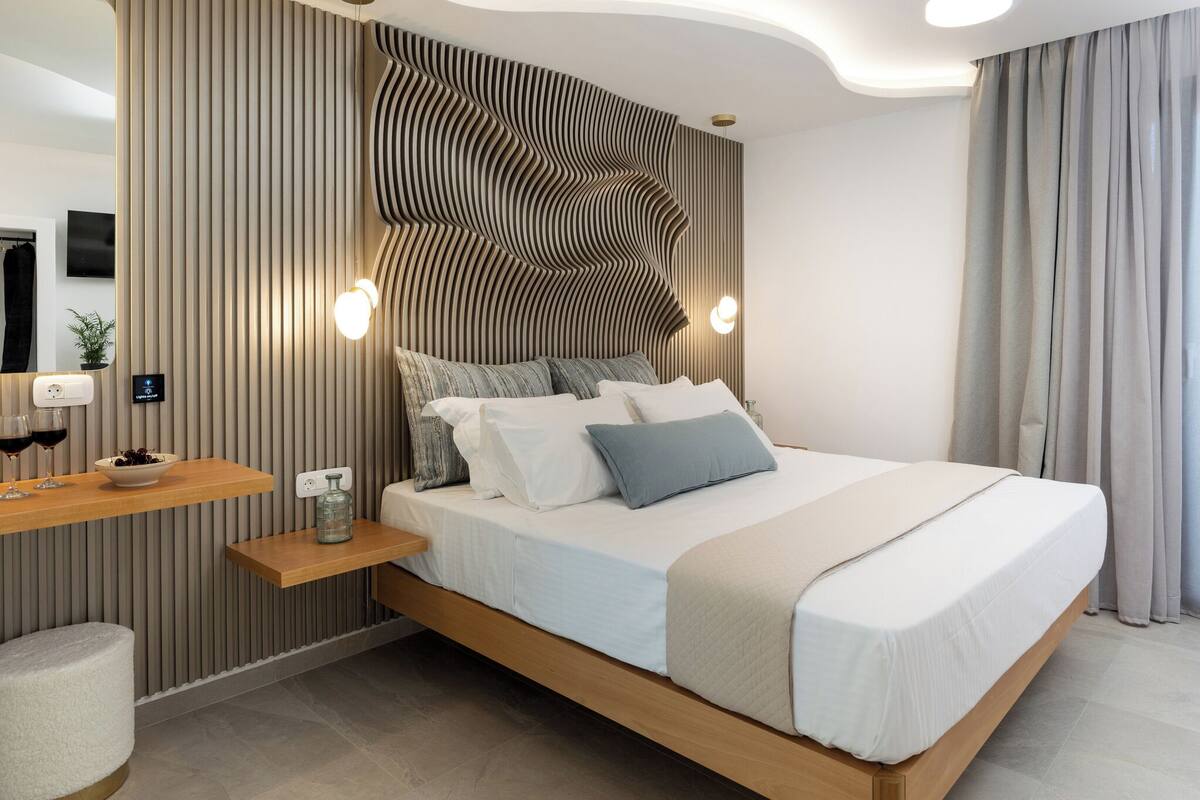 Quarto moderno com cama de madeira, mesa de cabeceira, luminária fixada na parede e sistema de som integrado.