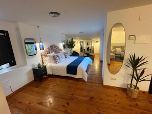 Um quarto moderno com uma cama grande, mesas de cabeceira, um espelho e um vaso com planta.