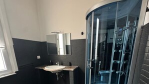 Casa de banho moderna com sanita, lavatório e cabine de duche envidraçada.