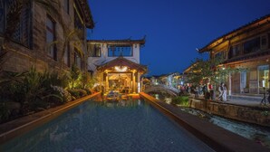 Um pátio tradicional com piscina, edifícios de pedra e uma ponte.