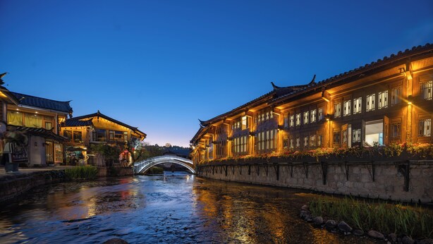 Um edifício tradicional com uma parede de pedra e uma ponte sobre um rio calmo.