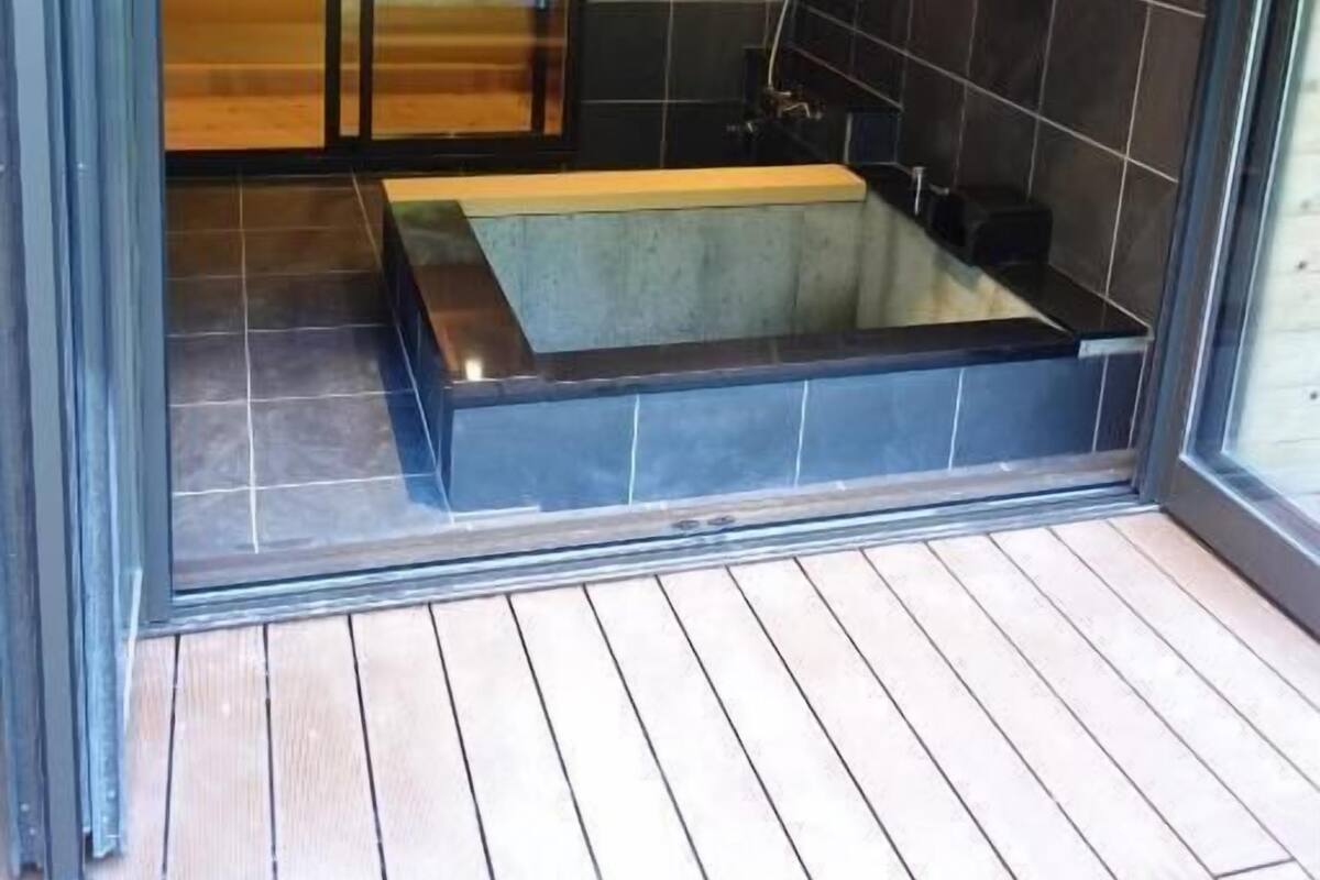 Um banheiro moderno com banheira, chuveiro e porta de vidro que dá para uma varanda.