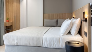 Quarto moderno com cama, luminárias de cabeceira, uma mesinha e um guarda-roupa de madeira.