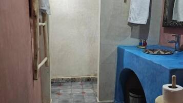 Um banheiro com pia azul, espelho, porta-toalhas e vaso sanitário.