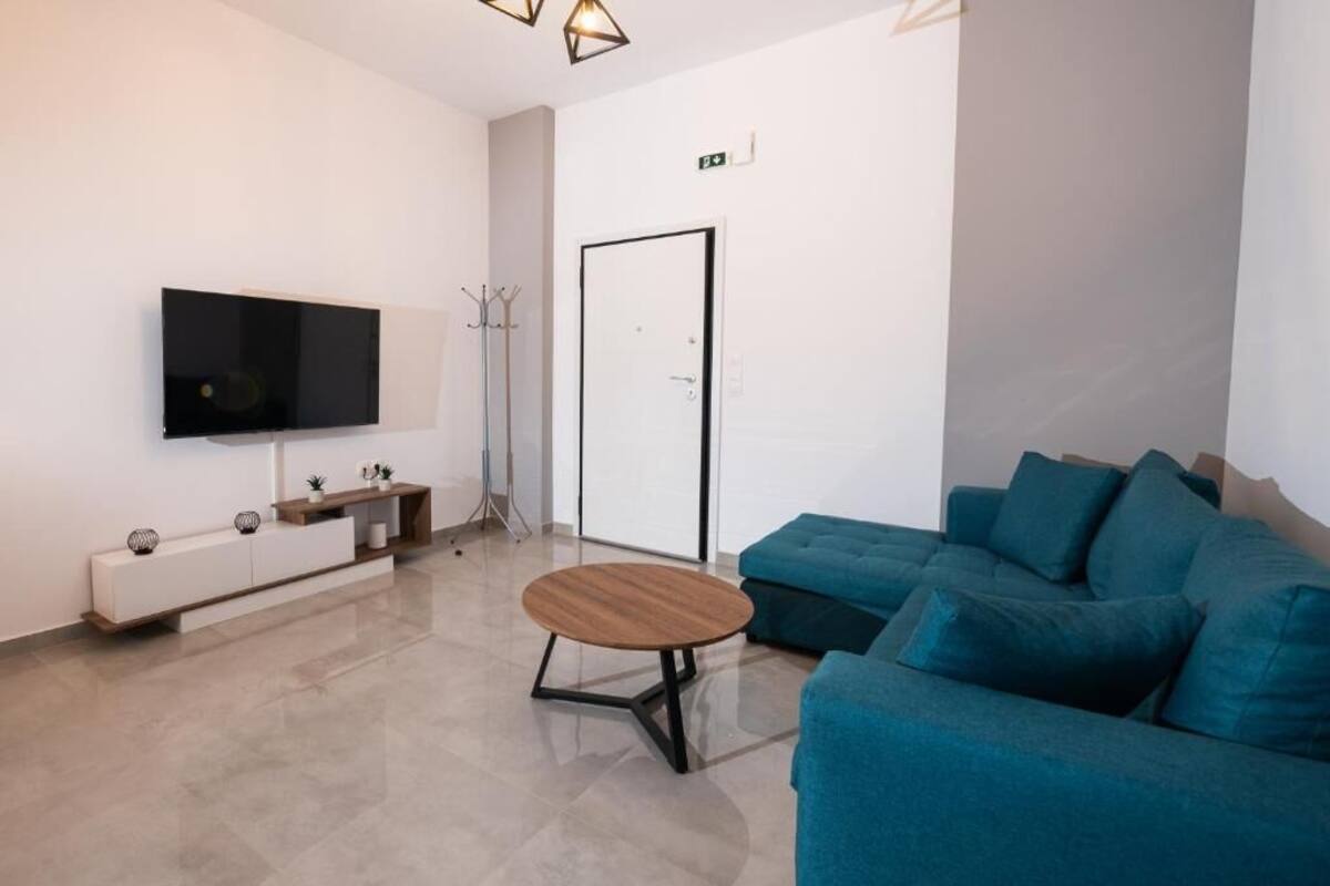 Uma sala de estar moderna com televisão de tela plana, um sofá, uma mesa de centro e um cabideiro.
