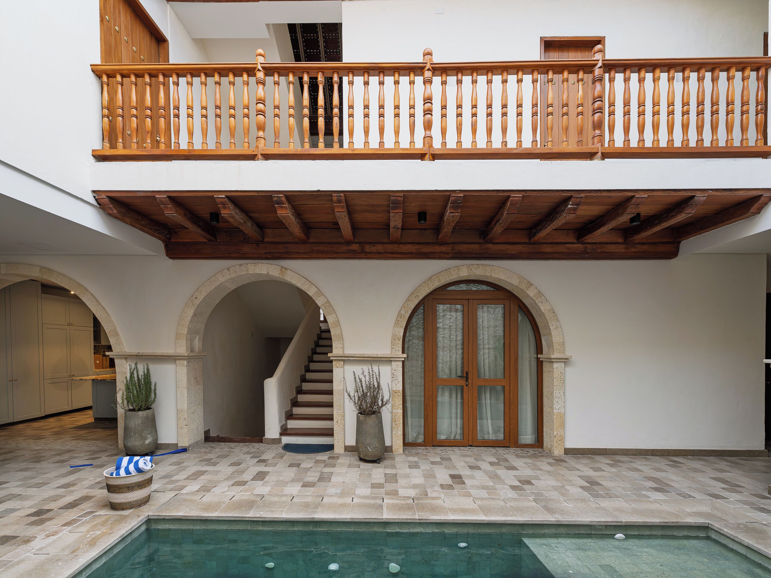 Uma área de piscina com varanda de madeira, escada e porta com painéis de vidro.