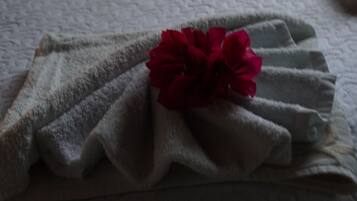 Uma toalha dobrada com uma flor vermelha sobre uma superfície branca texturizada.