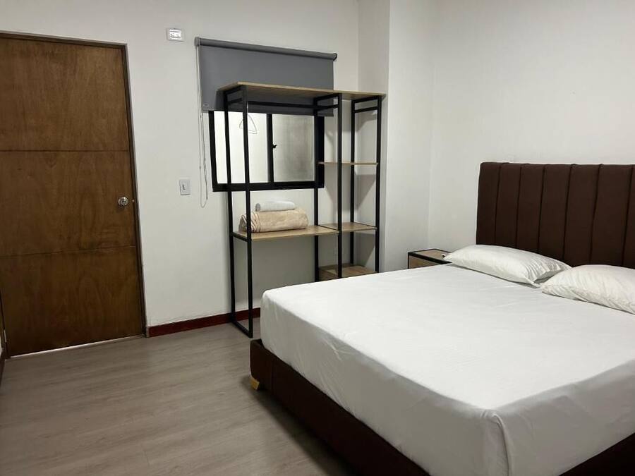 Um quarto com uma cama, um guarda-roupa, uma estante e uma mesa de cabeceira.