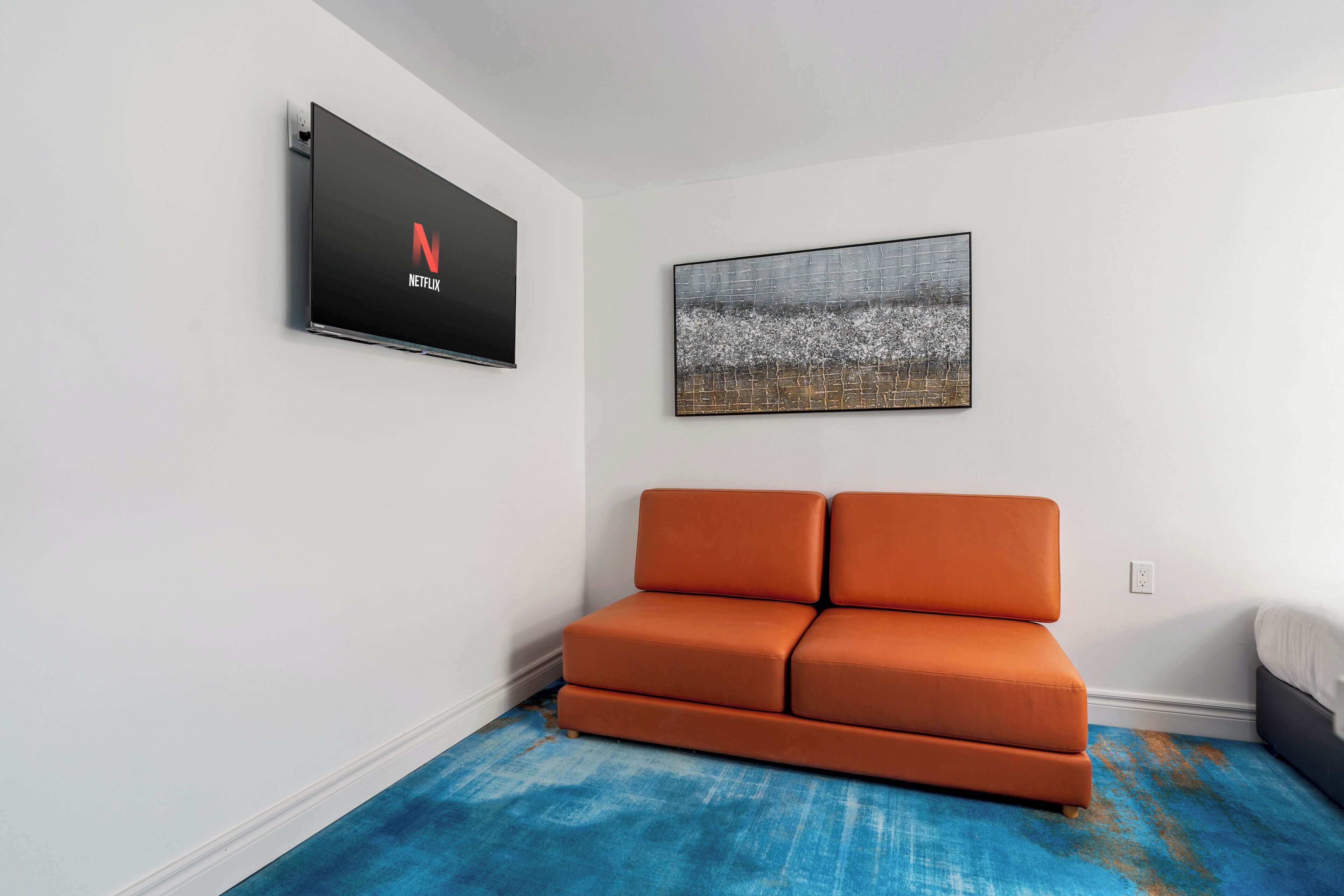 Quarto com sofá, televisão de tela plana e um quadro na parede.