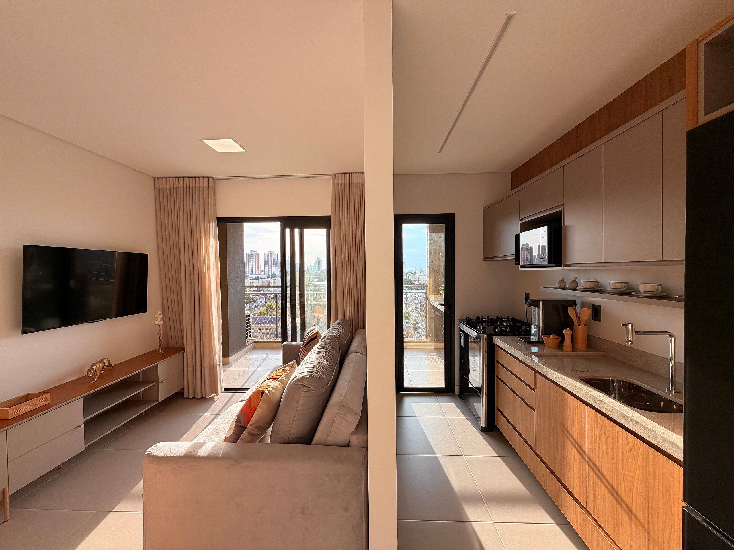 Apartamento moderno com sala de estar, cozinha e varanda com vista para a cidade.