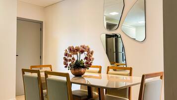 Sala de conferências com mesa, cadeiras, uma orquídea em vaso e espelhos na parede.