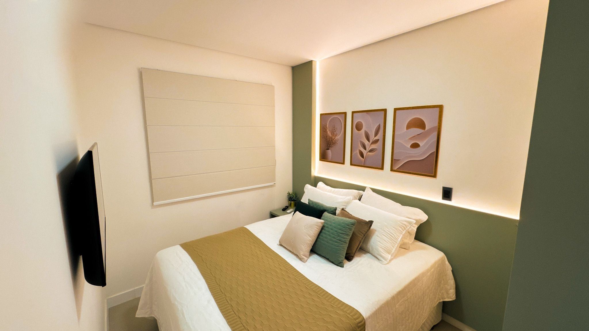 Quarto bem arrumado com cama, almofadas, mesa de cabeceira e decoração na parede.