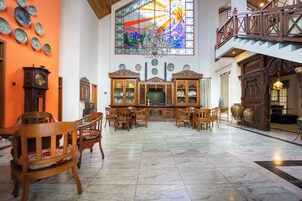 Um quarto amplo com uma grande janela de vitrais, móveis de madeira e uma escadaria.
