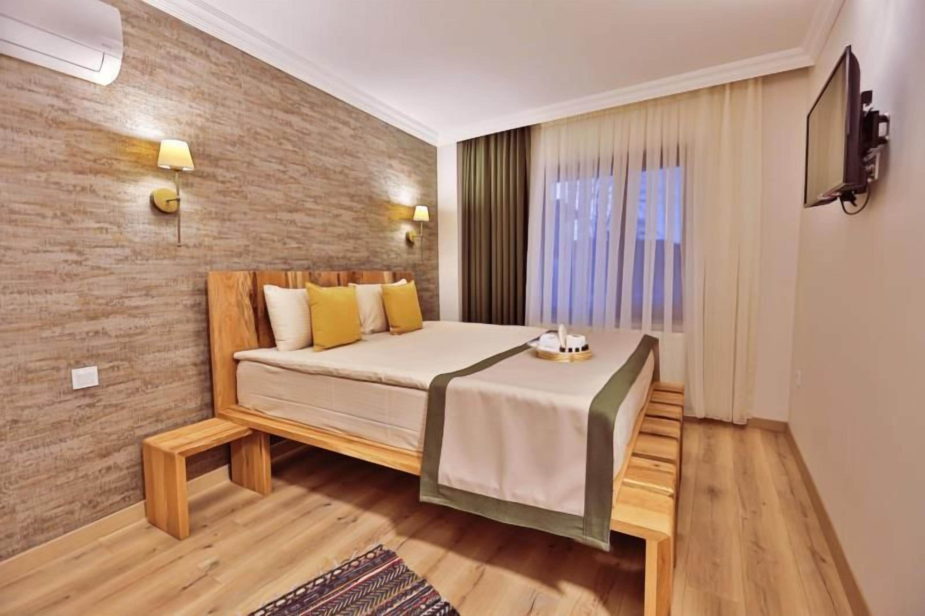 Quarto com cama de madeira, luminárias de cabeceira, mesa de cabeceira e janela com cortinas.
