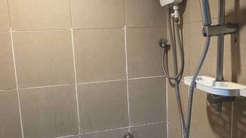 Área de duche com chuveiro manual, torneira embutida e painel de controlo.