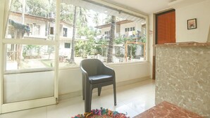 Um quarto com uma janela grande, uma cadeira de plástico, um balcão de mármore e uma porta.