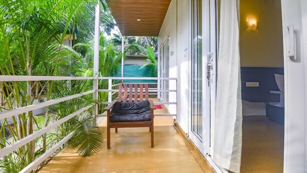Varanda com uma cadeira, teto de madeira e vista para uma piscina.