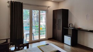 Quarto com porta de vidro deslizante, uma kitchenette pequena, uma mesa e uma cadeira.