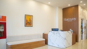 Uma receção com bancada de mármore, um banco de madeira e um quadro na parede.