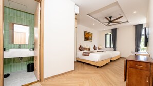 Quarto de hotel com chão de madeira, uma cama, escrivaninha, espelho e ventilador de teto.