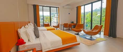 Quarto de hotel com duas camas, uma mesa de jantar e varanda com cadeiras laranja.