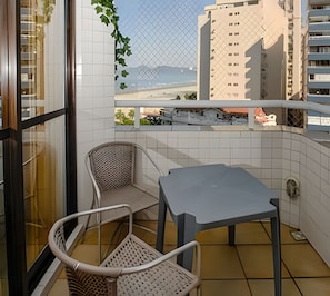 Uma varanda com vista para edifícios, uma mesa e duas cadeiras.