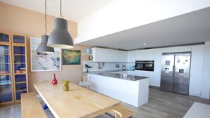 Cozinha moderna com ilha central, eletrodomésticos de aço inoxidável e iluminação pendente.