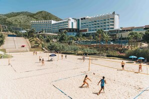 Uma quadra de voleibol de praia com um hotel ao fundo.
